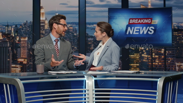 Broadcast presenters reporting news at late night television channel ...