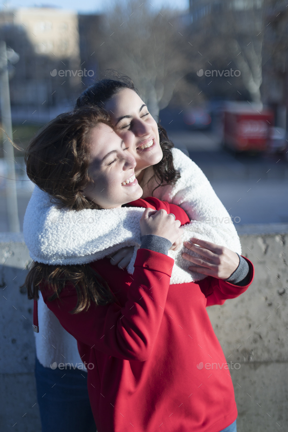 Joyful hug between two friends outdoors Stock Photo by raferto1973