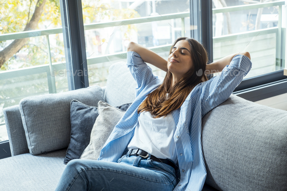 Front view portrait of a relaxed person smiling sitting on a couch in ...
