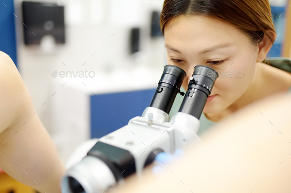 Gynecologist examines patient using microscope in gynecological chair ...