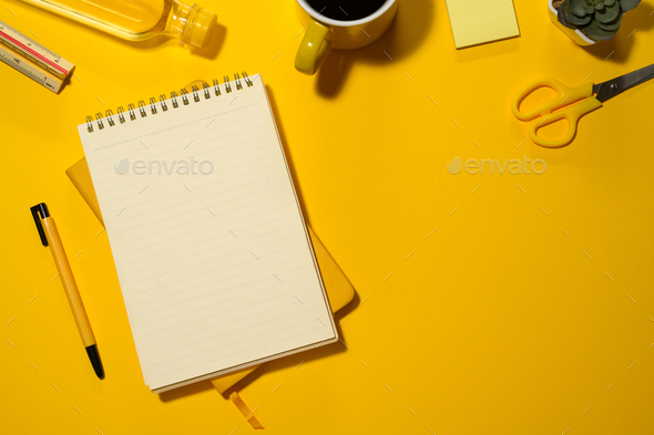 Blank spiral notepad, water bottle and stationery on yellow background ...