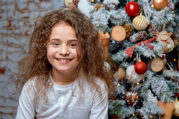 Young joyful girl smiling shyly over a brick wall crossed her arms ...