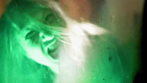 Scary ghost woman screaming through dirty glass on dark background ...