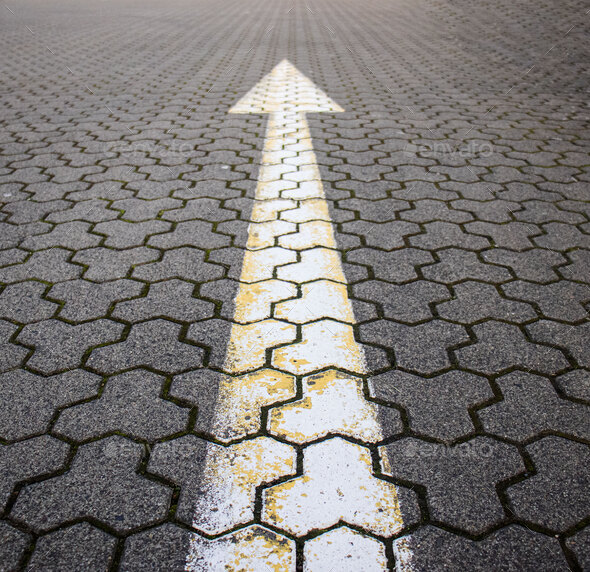 road markings, arrow on the road made of paving stones, indicating the ...