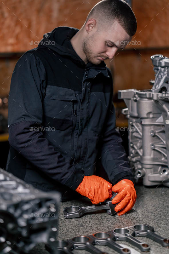 At a service station on the table young engine repairman assembles a ...