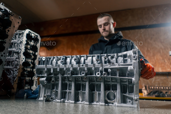 At service station on the table young engine repairman manually cranks ...