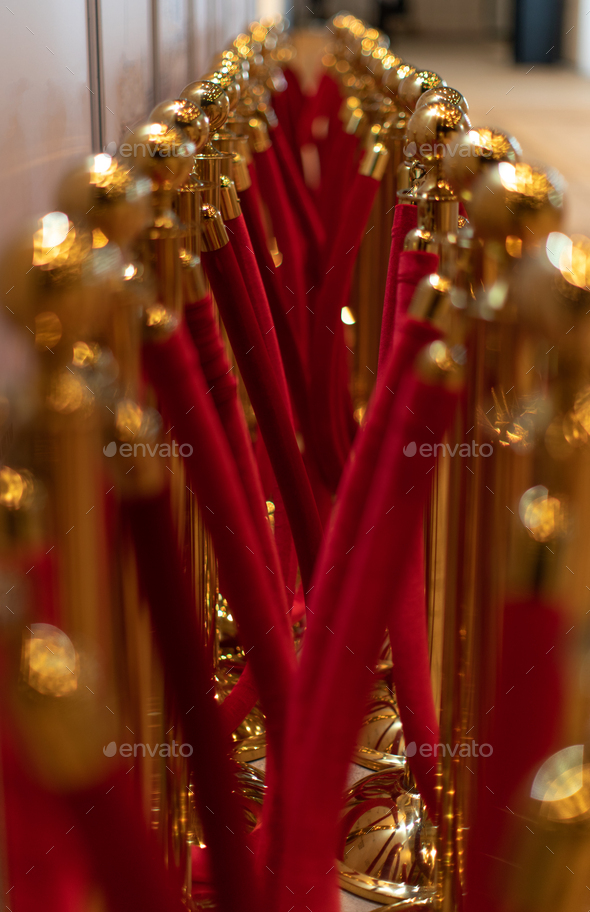 many folded golden Stanchions with red velvet ropes selective focus ...