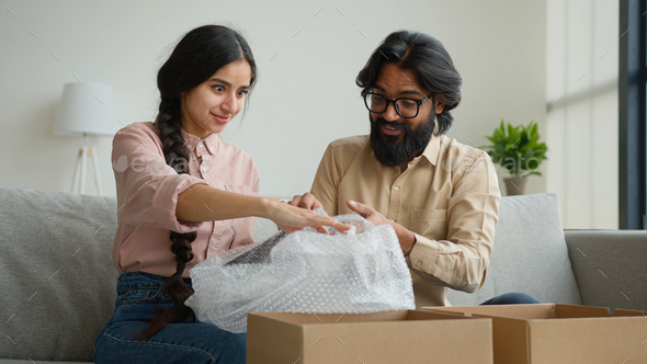Excited diverse customers couple opening parcel at home happy clients ...