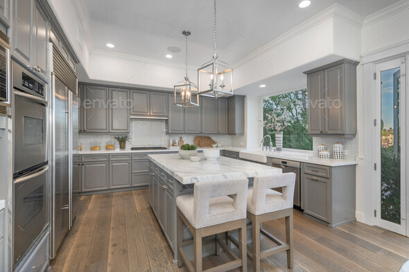 Modern kitchen with marble countertops, wooden floors, light gray ...