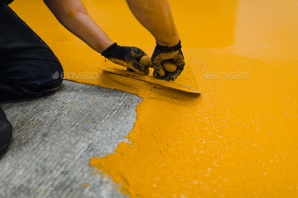 Professional construction worker applying floor paint or a new layer ...