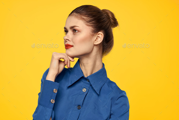 portrait of a strict woman in a blue shirt with red lips on a yellow ...