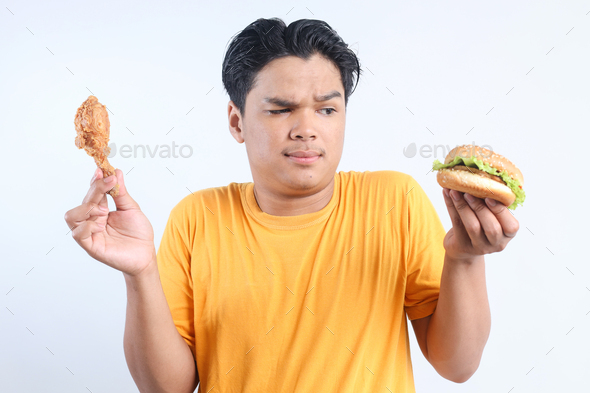 Confused Asian Man Compare Fried Chicken and Burger Stock Photo by ...