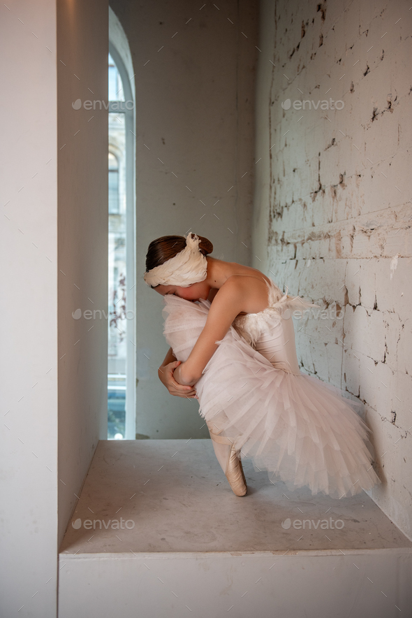 Captured in soft light, ballerina in thoughtful pose reflects quiet ...
