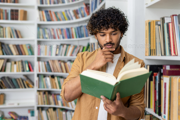 Focused student immersed in reading a book in library Stock Photo by ...