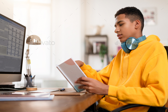 Focused young man reading a paper at home office desk Stock Photo by ...