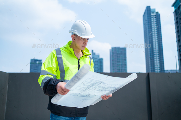 Construction Engineer Evaluating Blueprints on Rooftop Stock Photo by ...