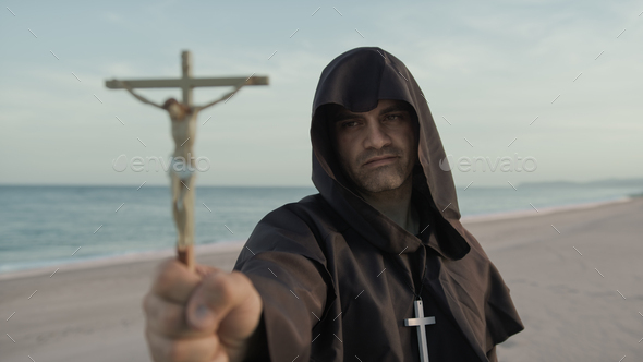 Monk With Statuette Of Jesus In His Hand Prays Stock Photo by PolonioVideo