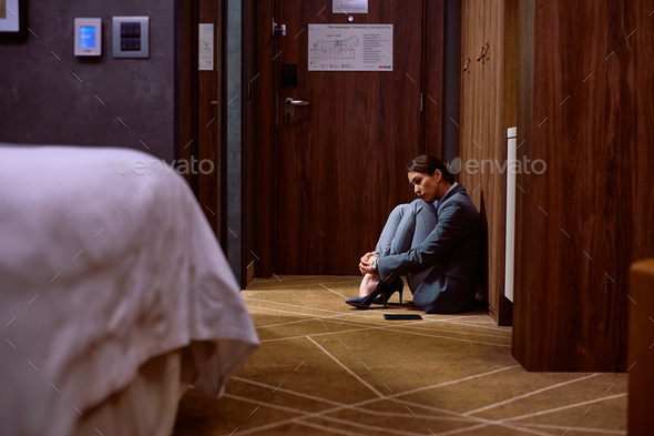 Sad businesswoman sitting on the floor in a hotel room. Stock Photo by ...
