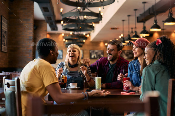 Group of happy friends laughing while gathering in a pub. Stock Photo ...