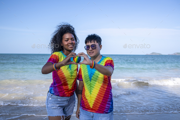 LGBTQ couple lover pose happiness show heart rainbow color on beach in ...