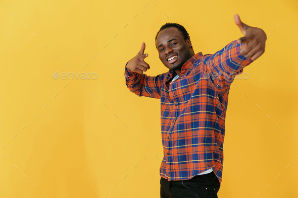 Making hand gestures. Black man is in the studio against yellow ...