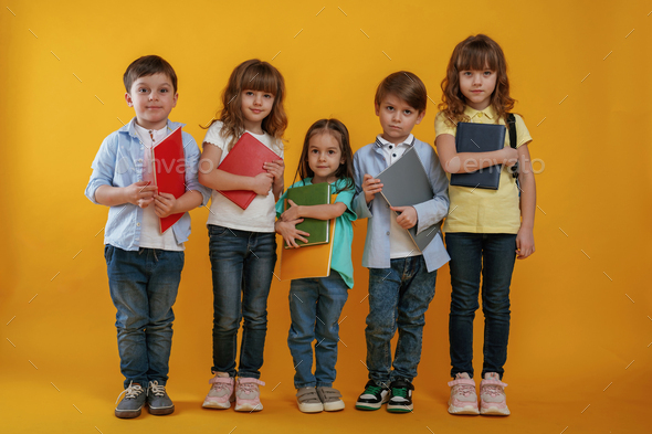 Standing and posing. Kids are together against yellow background Stock ...