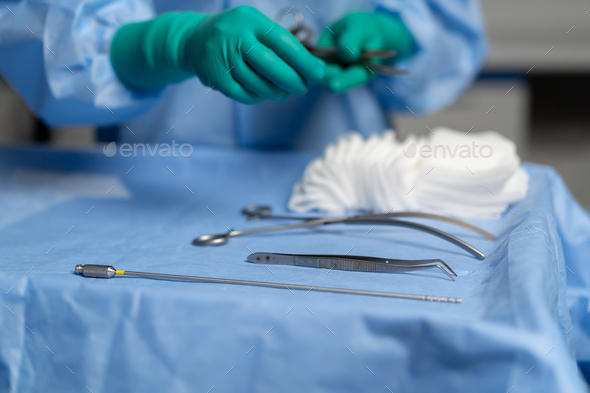 operating room the in green gloves lays out instruments on the surgical ...
