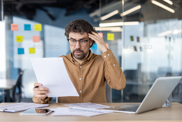 Confused mature businessman reviewing documents at desk Stock Photo by ...