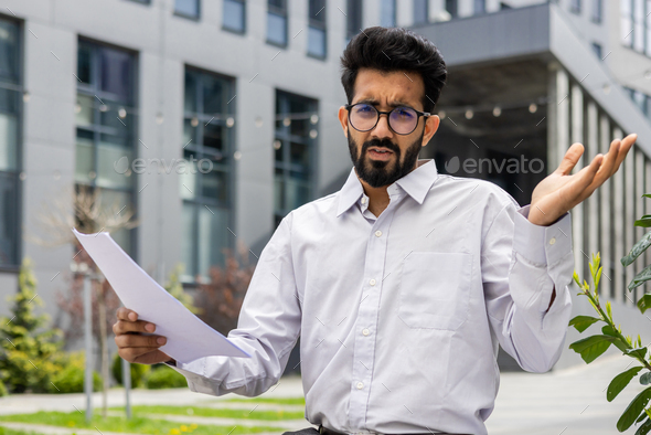 Portrait of an upset and disappointed young Indian man sitting outside ...