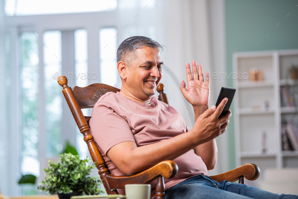 mid age Indian asian man with grey hair using smartphone while sitting ...