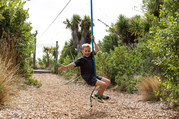 The boy is flying on a zip line in the park. A child is happily rocking ...