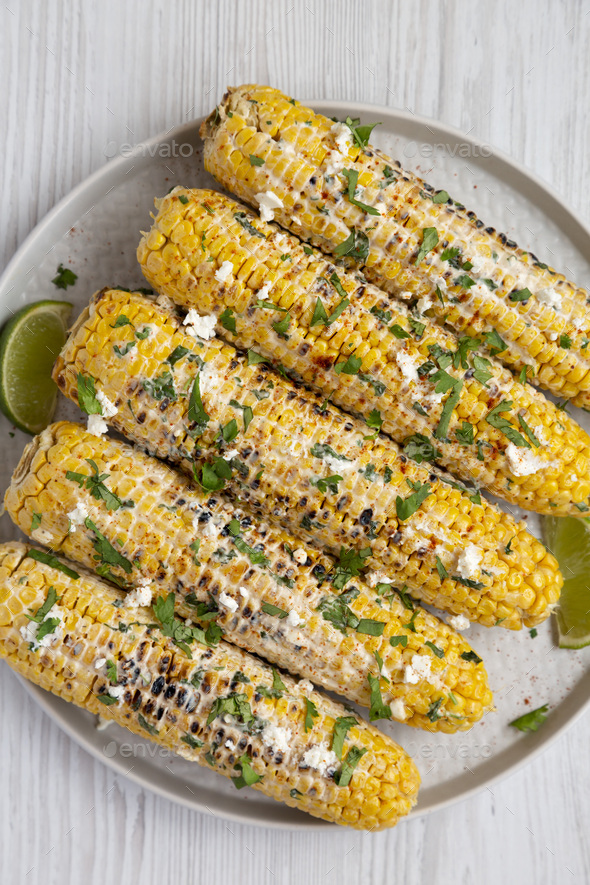 Homemade Elote Mexican Street Corn on a plate on a white wooden surface ...