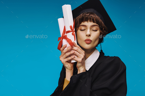 happy grad college girl in gown and academic cap holding diplomas with ...