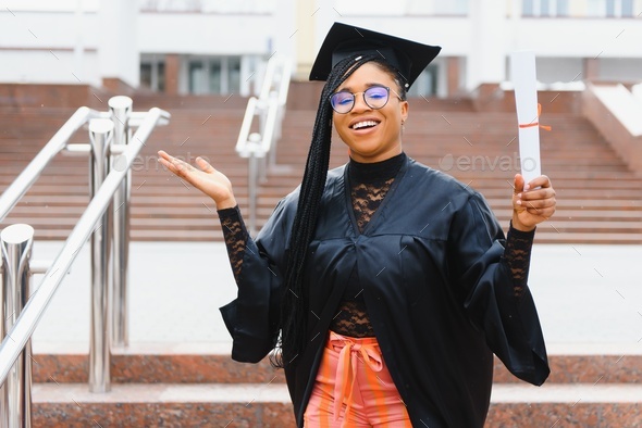 happy african american female student with diploma at graduation Stock Photo by sedrik2007