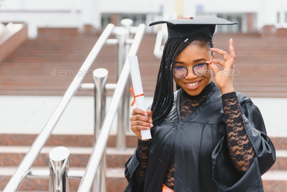 happy african american female student with diploma at graduation Stock Photo by sedrik2007
