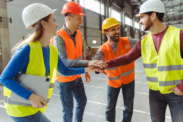 Happy managers wearing hard hats and vests, teamwork join hands ...