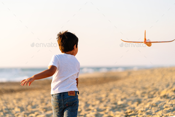 Chasing the Wind: Boy Running with Airplane on the Beach at Sunset ...