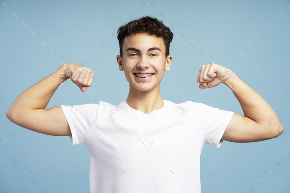Smiling strong teenage boy wearing stylish white t shirt showing ...
