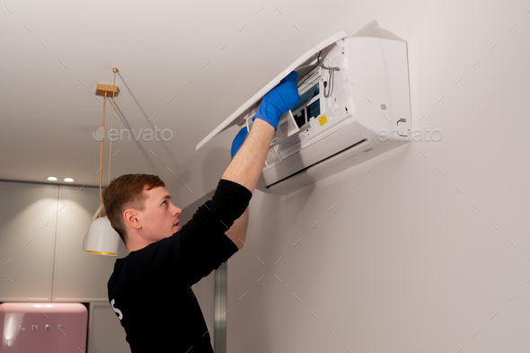 in the apartment the cleaner is cleaning the filters in air conditioner ...