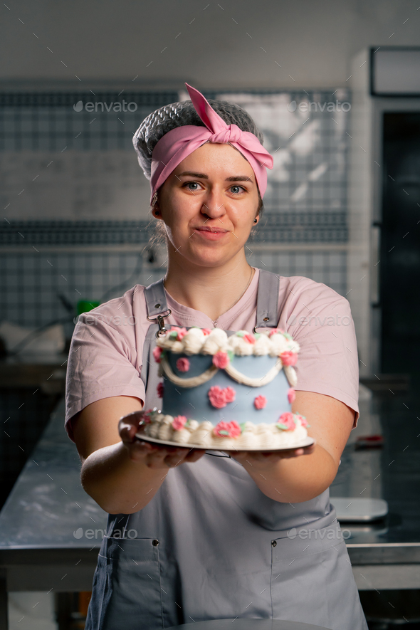 close-up in professional kitchen a female baker stands with a finished ...