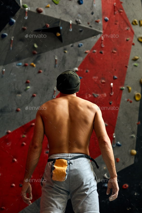Back side of athlete man standing next to wall, ready for rock climbing ...