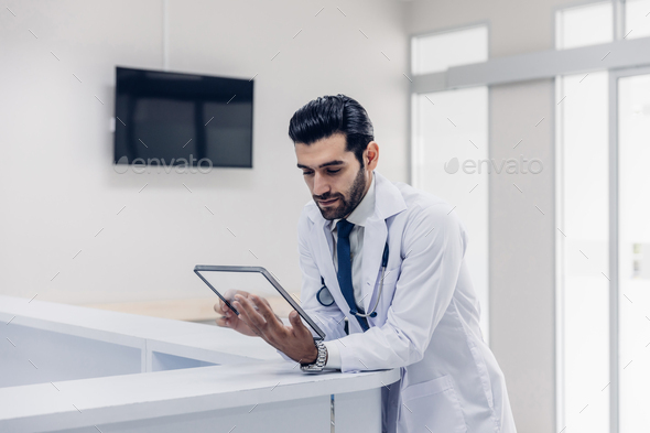 Doctor Wearing Scrubs In Hospital Corridor Using Digital Tablet. Stock ...