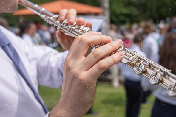 close-up view of a musician's hands playing a flute at an outdoor ...