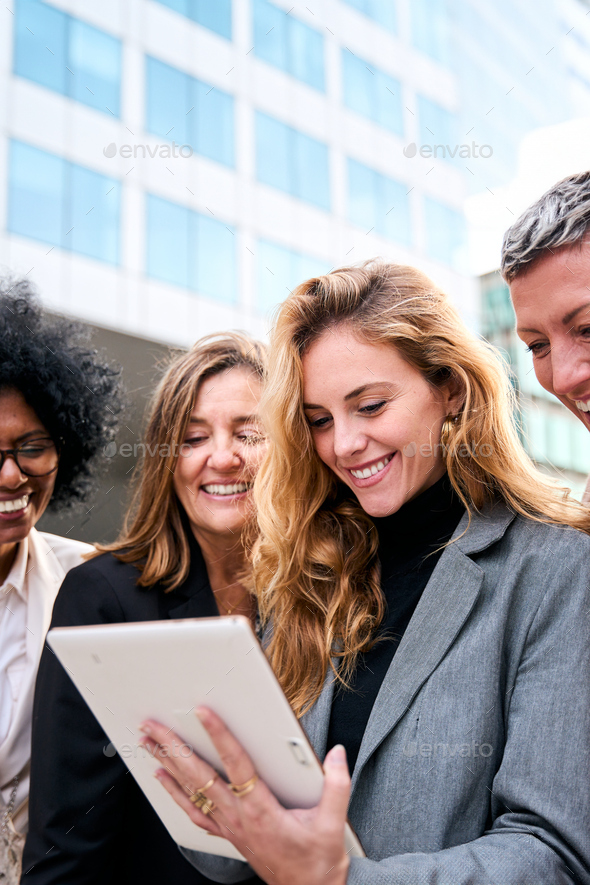 Cheerful group of multiracial women gathered using a mobile cell phone ...