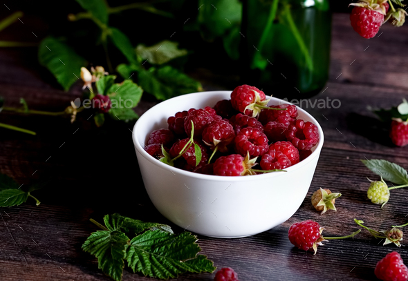 Cup full of fresh ripe garden raspberries against dark rustic ...