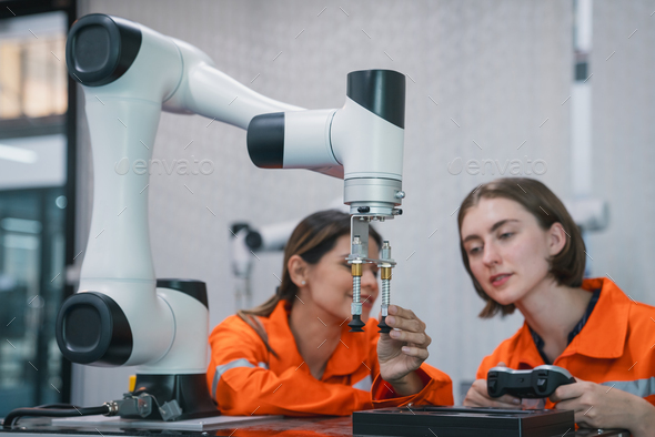 Engineering student assembling a robotic arm using a computer in a ...