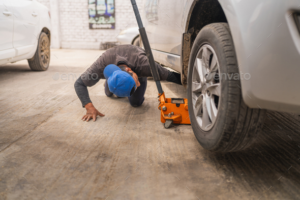 Mechanic elevating a car with manual lift Stock Photo by GSR-PhotoStudio
