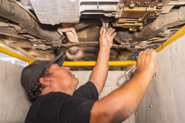 Mechanic looking into the engine of a car standing underneath Stock ...