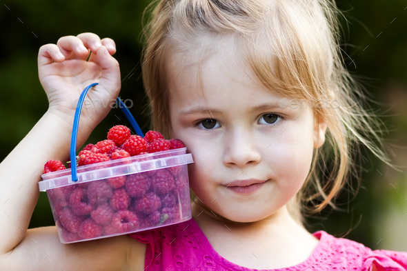 Portrait of a little girl child holdind small basket of ripe ...