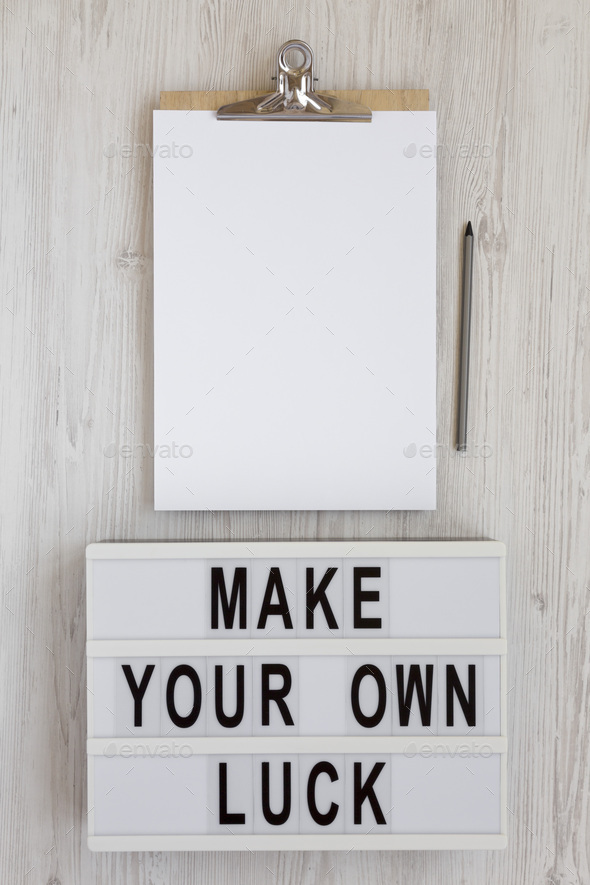 'Make your own luck' on a lightbox, clipboard with blank sheet of paper ...